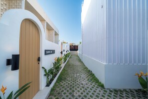Um caminho estreito com piso de azulejos que leva à entrada de um prédio.