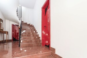 Uma escada com corrimão leva a uma porta vermelha.