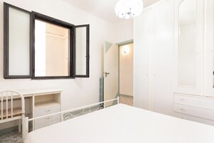 Quarto com cama, escrivaninha, cadeira e guarda-roupa.