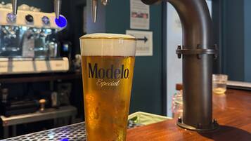 Uma torneira com cerveja Modelo e um copo de cerveja em um balcão de bar.