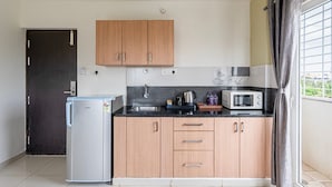 Cozinha compacta com geladeira, micro-ondas e armários de madeira.