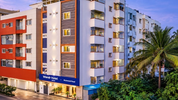 Um hotel moderno com vários andares, com varandas e área de piscina visível.