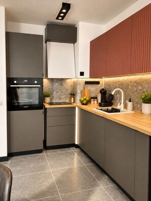 Cozinha moderna com forno Bosch, bancada de madeira e pia embutida.