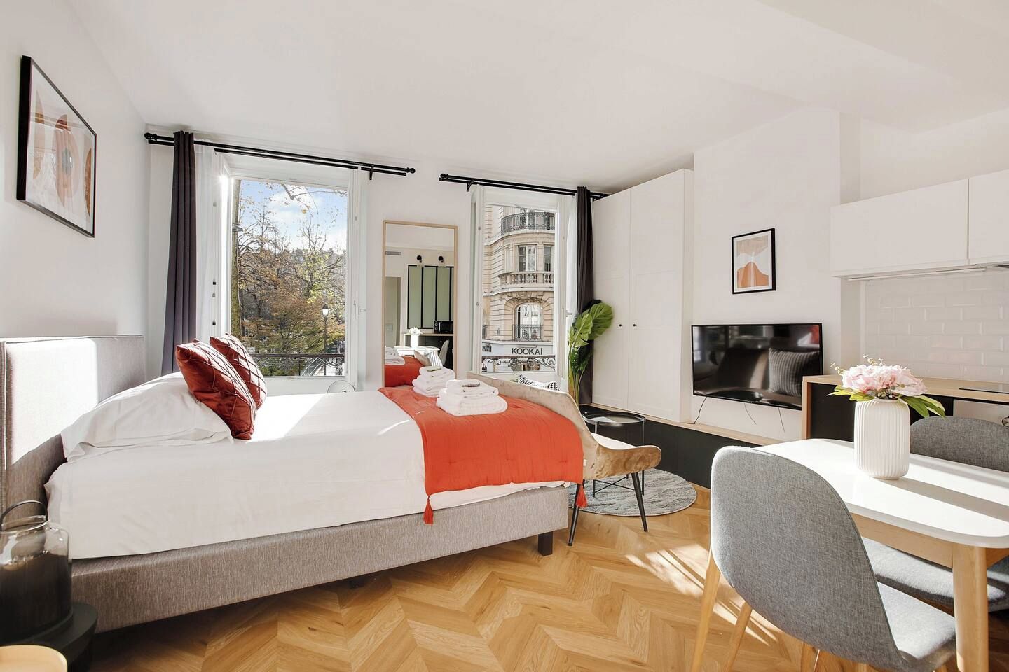 Quarto de hotel moderno com uma cama grande, uma escrivaninha, uma televisão e vista para a cidade.