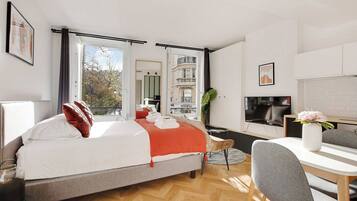 Quarto de hotel moderno com uma cama grande, uma escrivaninha, uma televisão e vista para a cidade.