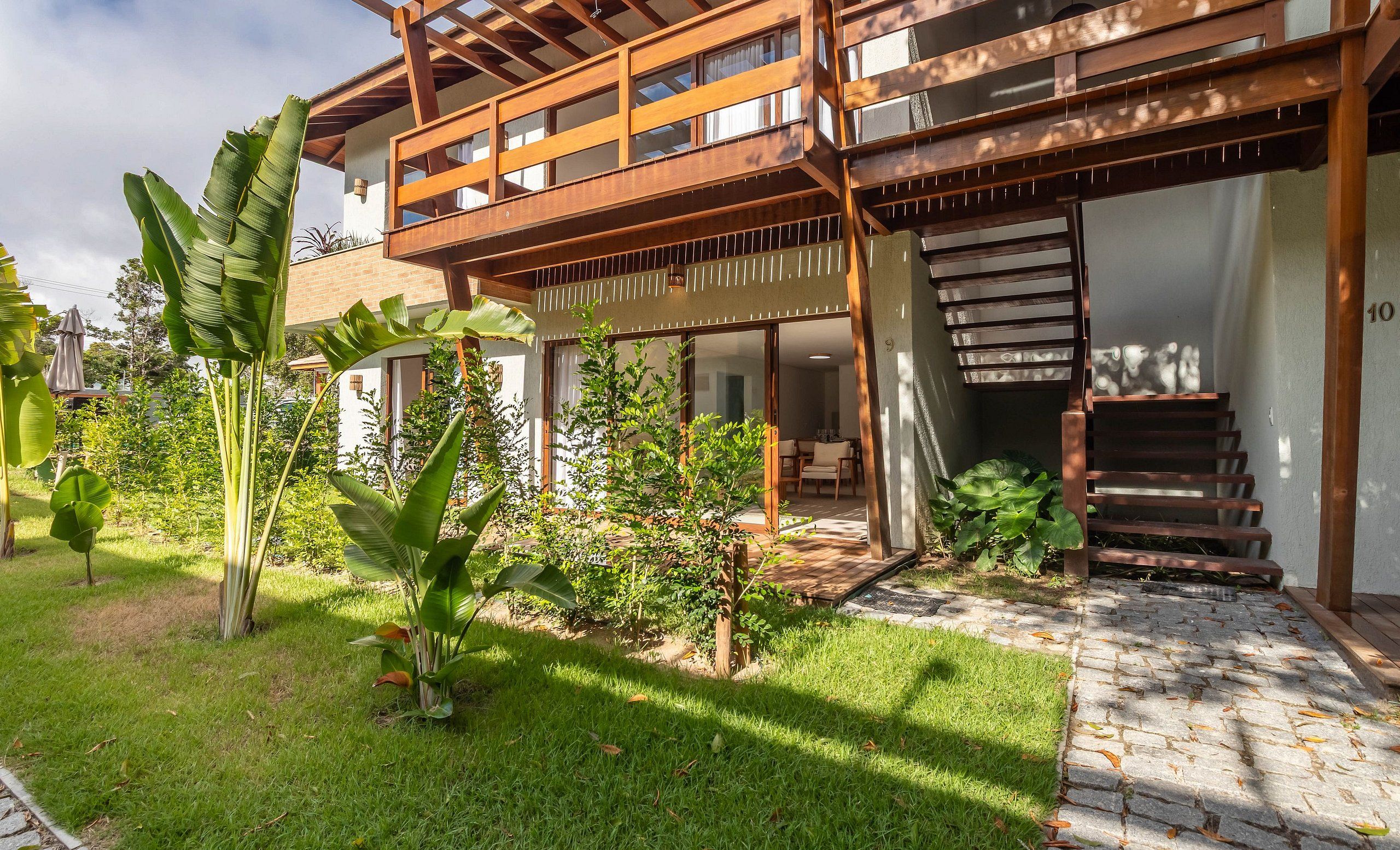 Uma casa de dois andares com varanda coberta e escada para o andar superior.