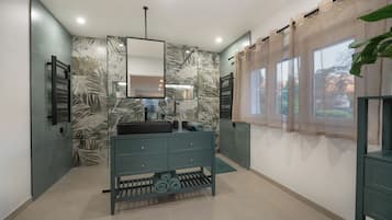 Casa de banho com design moderno, destacando um espelho grande, lavatório e suporte para toalhas.