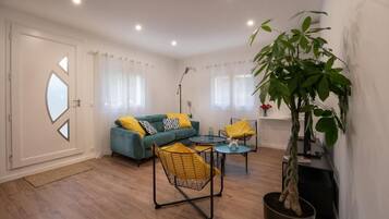 Sala de estar com sofá, duas poltronas, mesa de centro e planta em vaso.