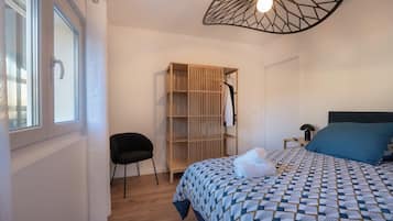 Quarto com cama, cadeira, guarda-roupa e luminária pendente.