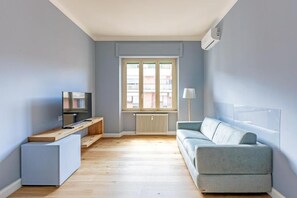Uma sala de estar moderna com sofá, TV e janela com persianas.