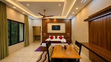 Quarto de hotel moderno com cama, mesa de jantar, cadeiras, ventilador de teto e televisão na parede.