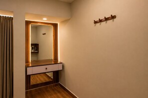 Casa de banho com toucador de madeira, espelho com iluminação integrada, porta-toalhas e chão em madeira.