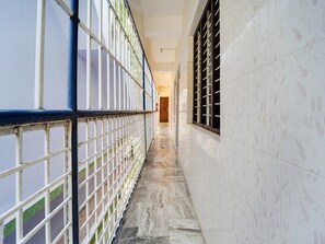 Um corredor com piso de azulejos, corrimãos de metal e uma porta no final.
