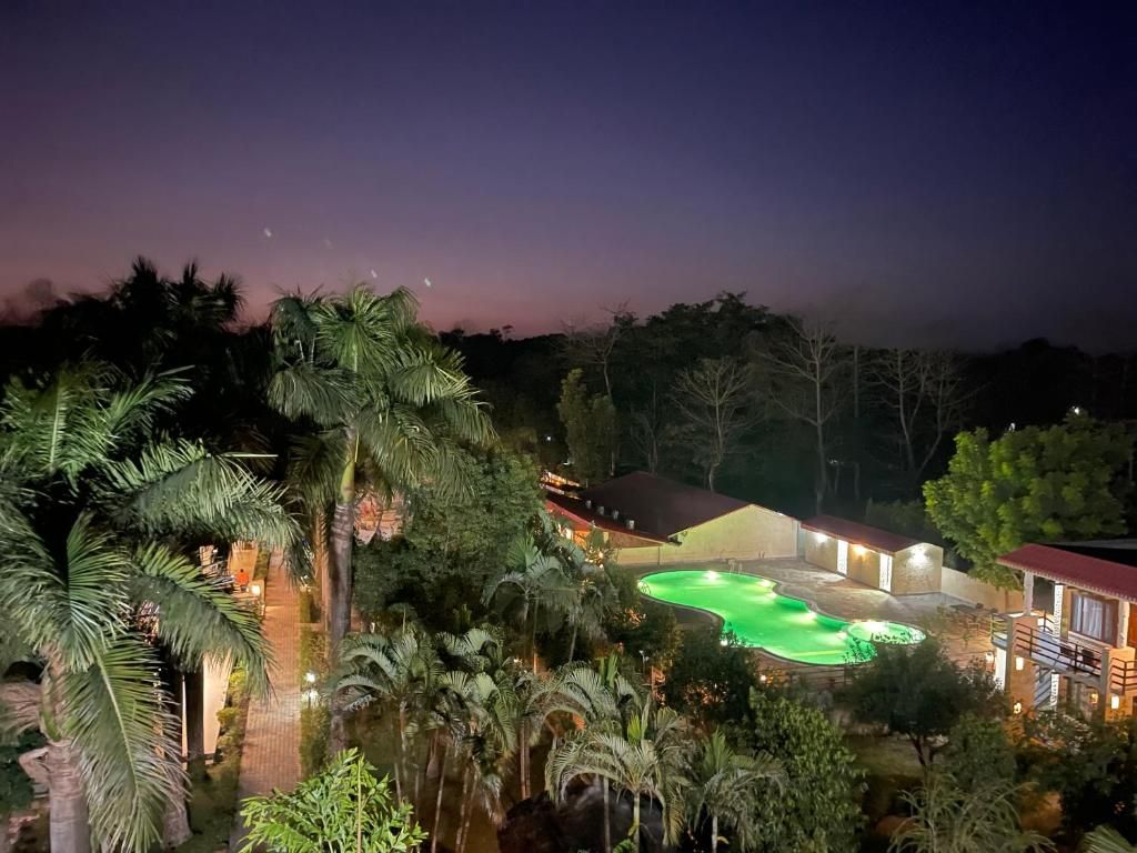 Resort com piscina, cercado por palmeiras e um edifício com telhado vermelho.