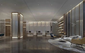 Um lobby moderno com balcão de recepção, área de estar e uma grande estante de livros.