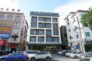 Um edifício de vários andares com uma placa indicando 'Paco Hotel', identificando-o como um hotel.