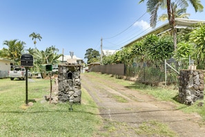 Bairro residencial com caixa de correio de pedra, entrada de automóvel pavimentada e casa com quintal cercado.