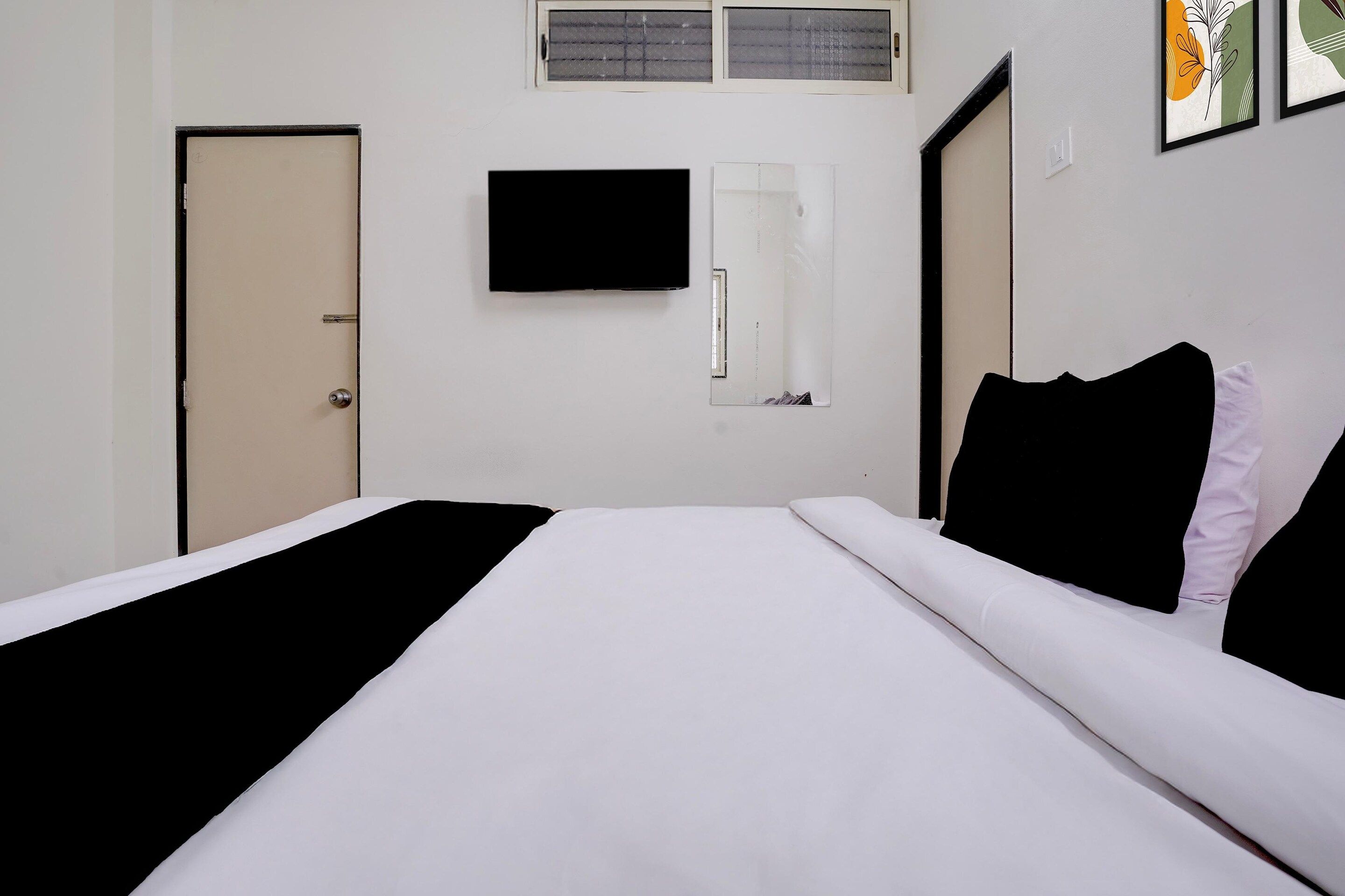 Quarto com cama, porta, janela e televisão fixada na parede.
