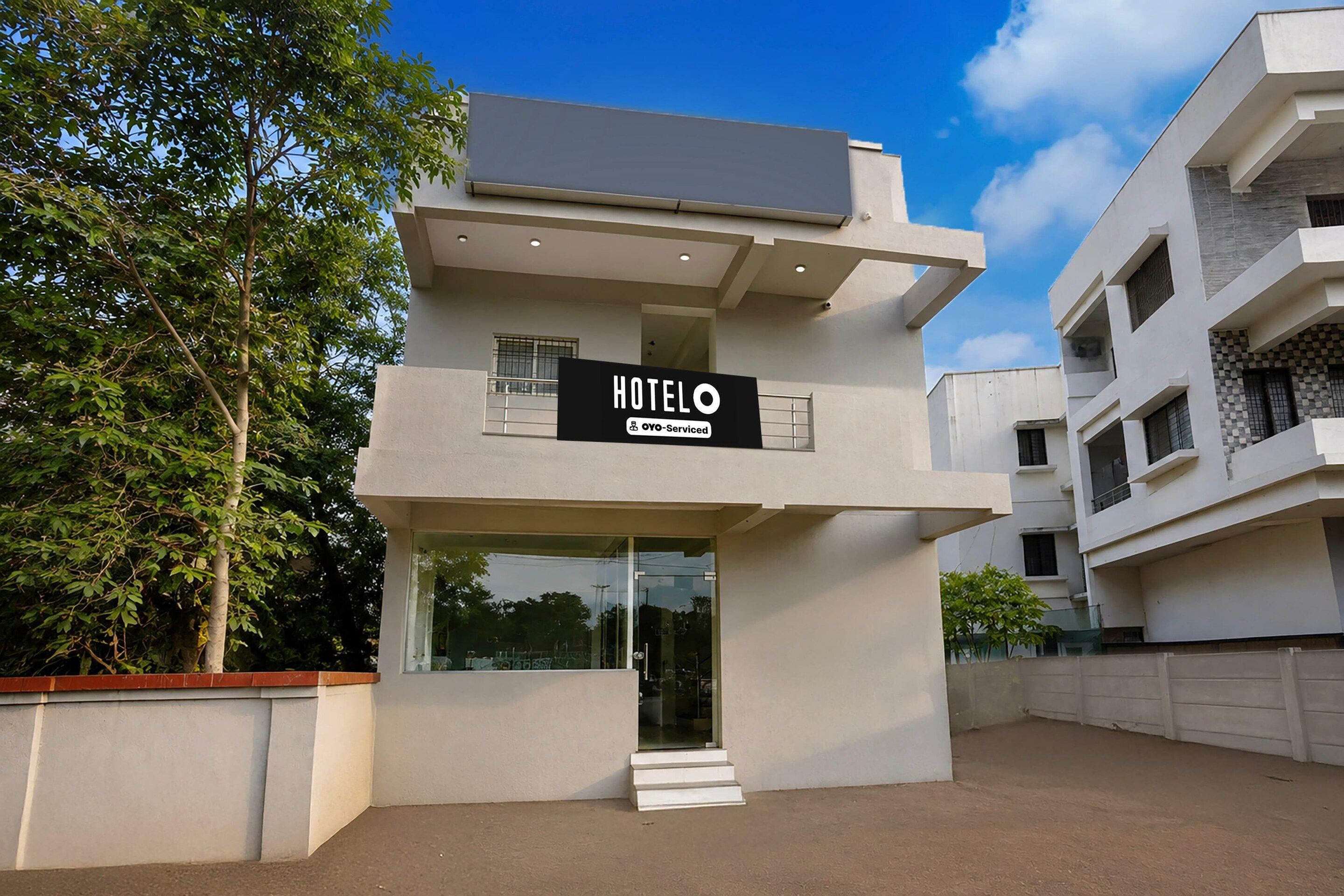 Um edifício moderno de hotel com uma placa que diz 'HOTELO' e 'OYO-SERVICED'.