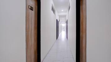 Um corredor comprido e estreito com portas de madeira em ambos os lados e piso de azulejos.