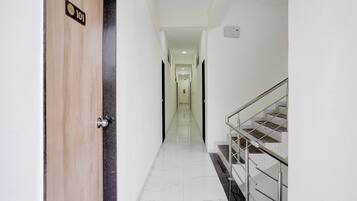 Corredor de hotel com porta de madeira identificada com o número '101', piso de mármore e escada com guarda-corpos de metal.