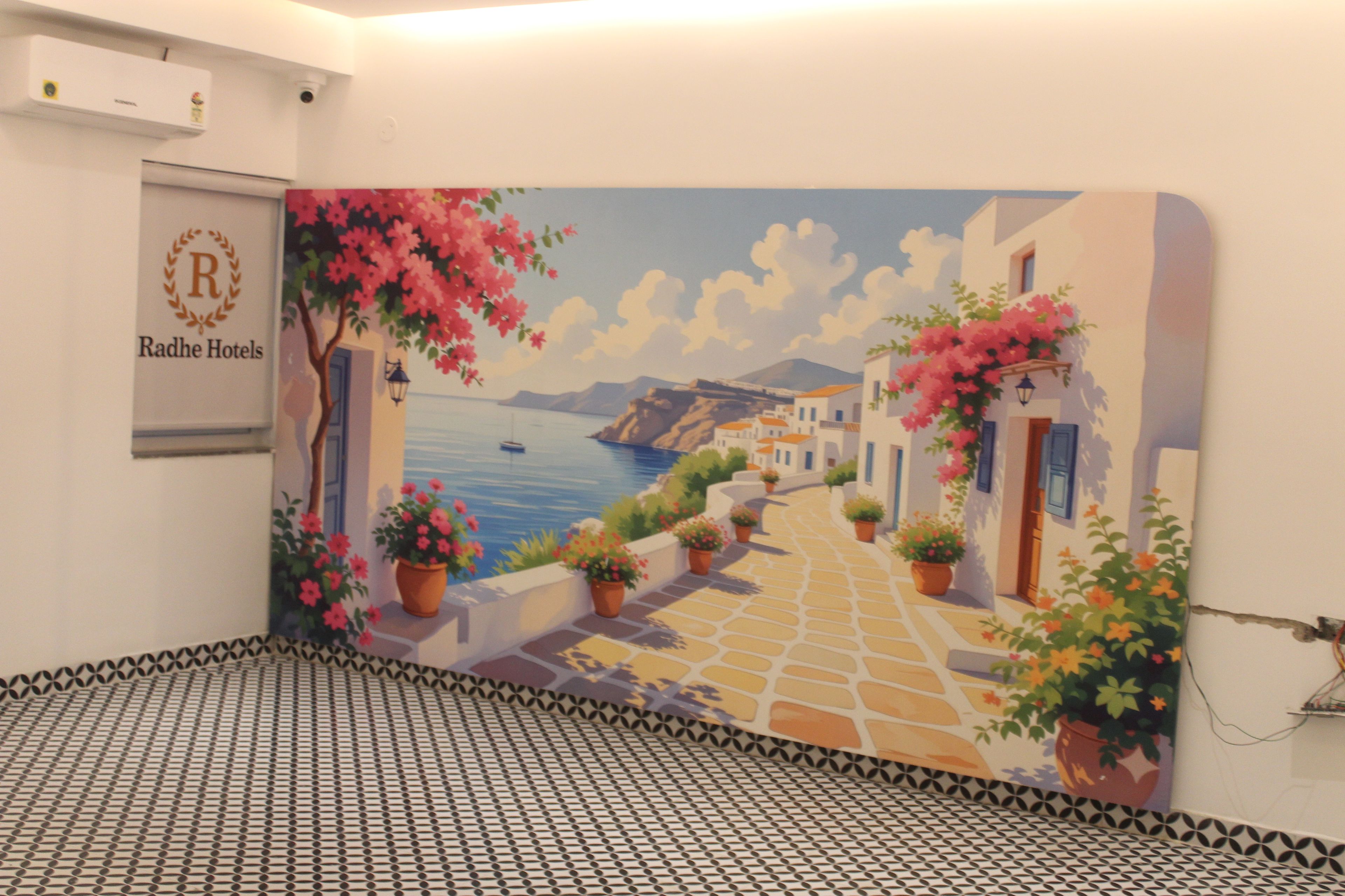 Interior de hotel com um mural de uma paisagem costeira, uma mesa de recepção e piso estampado.