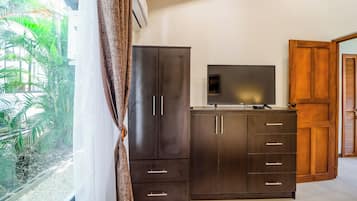 Quarto com guarda-roupa de madeira escura, uma TV de tela plana em cima e uma porta de madeira.