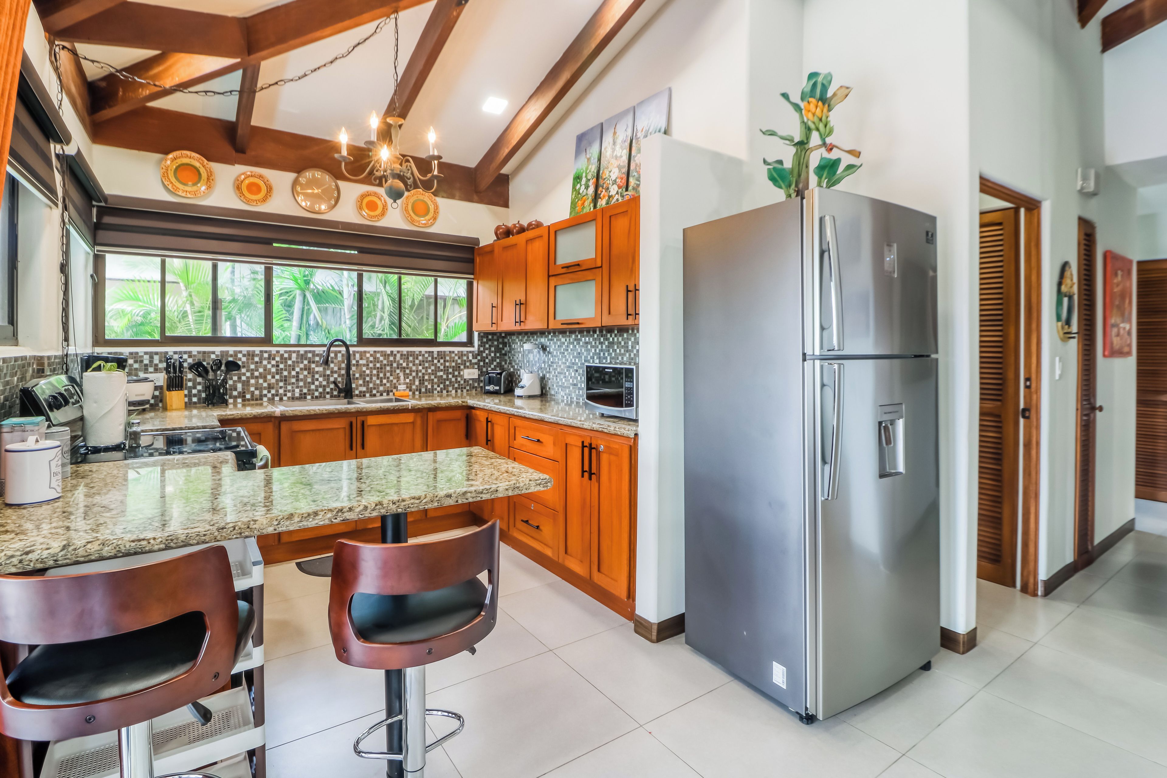Cozinha moderna com bancadas de granito, armários de madeira e geladeira de aço inoxidável.