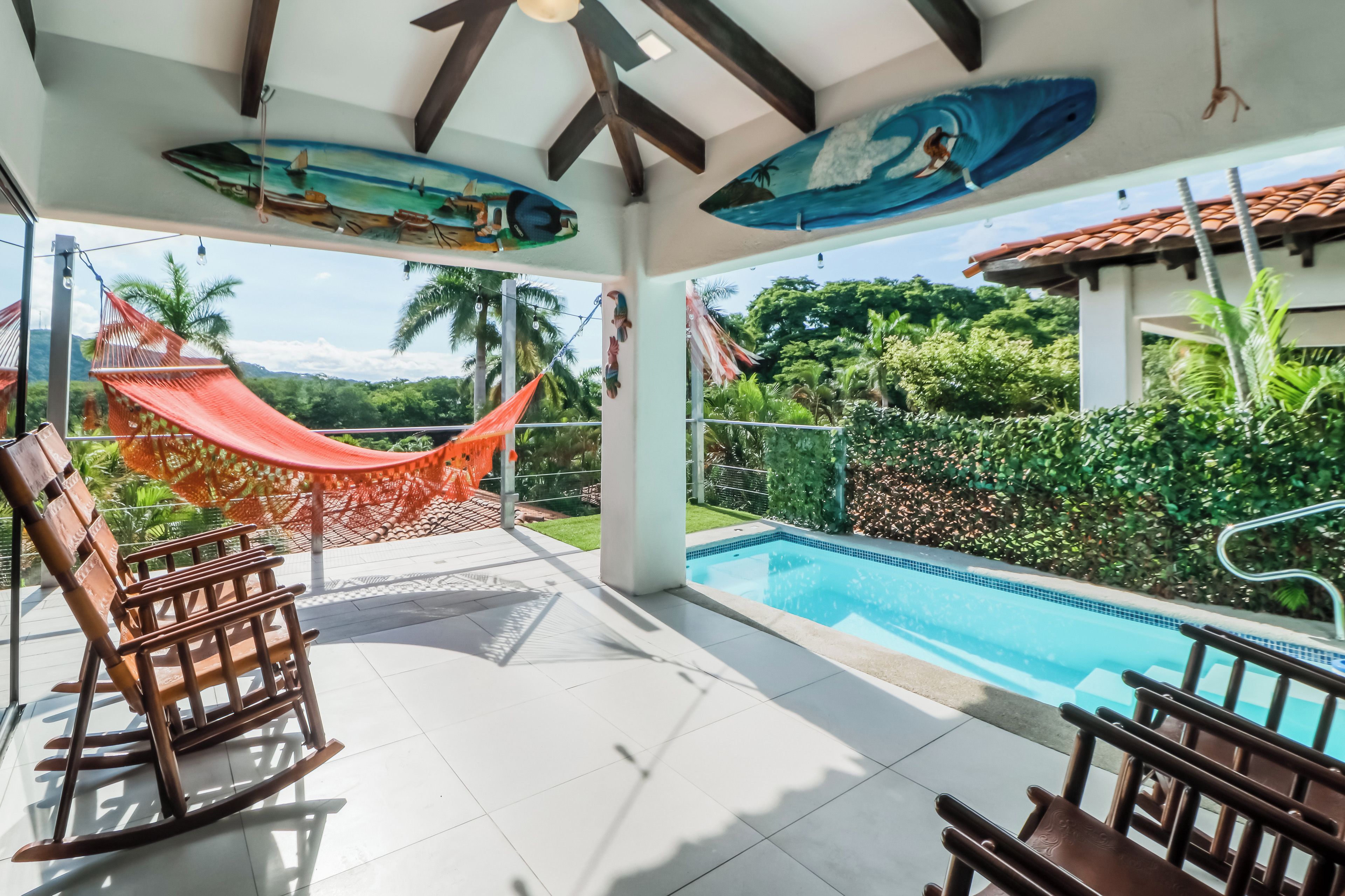 Área de piscina com rede, cadeiras e vista para o verde ao redor.