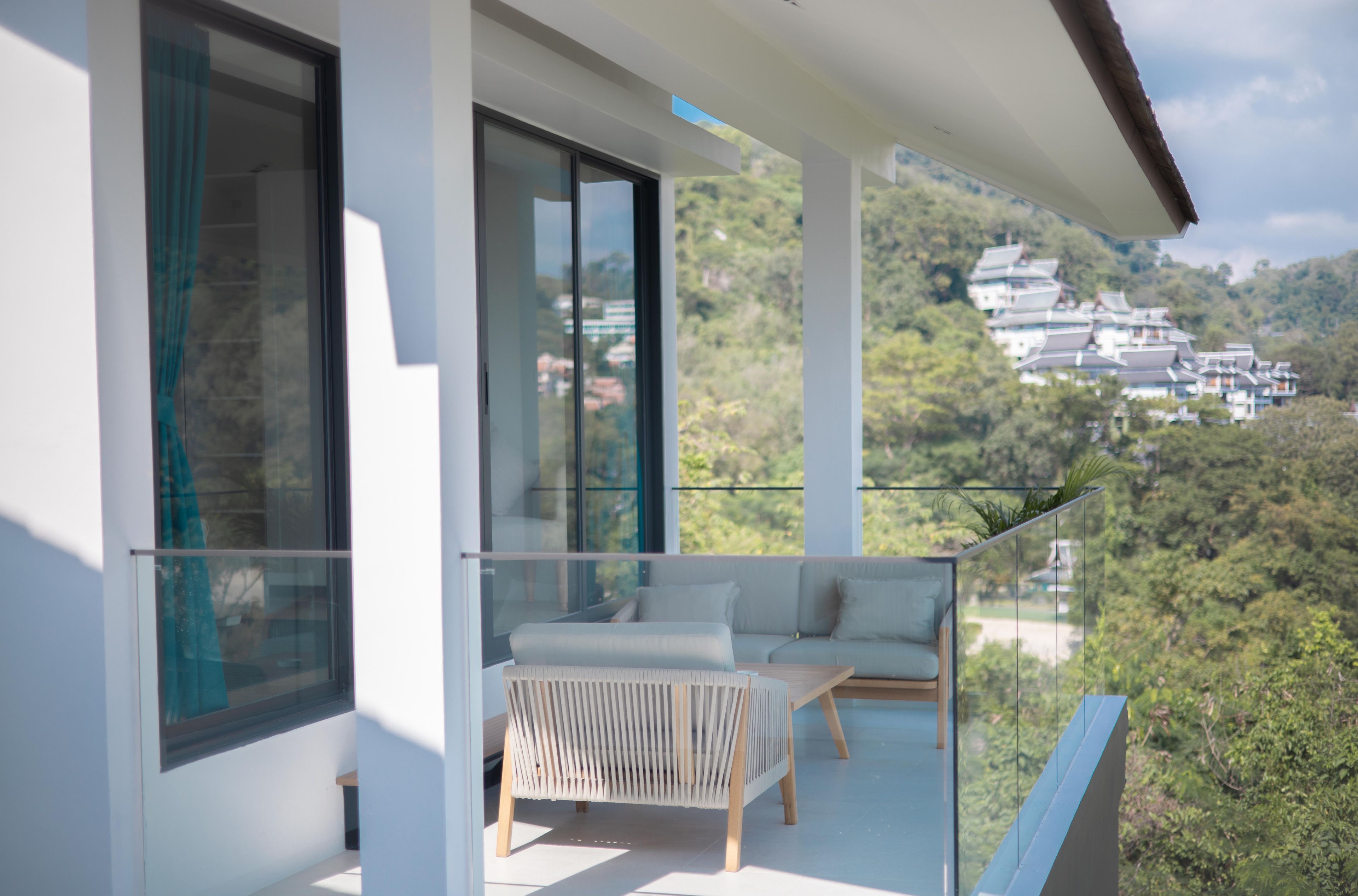 Varanda com sofá e mesa, com vista para um morro com edifícios tradicionais.