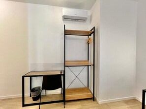 Quarto com escrivaninha, cadeira e estante escalonada em parede branca.