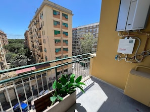 Varanda com planta em vaso, aquecedor e vista para um prédio residencial.
