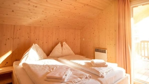 Quarto de cabana de madeira com duas camas, uma janela e um aquecedor.