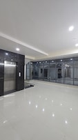 Um hall amplo com elevador moderno e paredes de vidro.