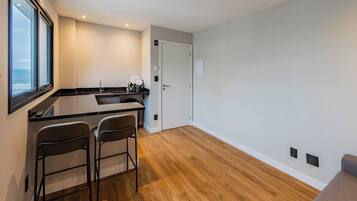 Cozinha moderna com bancada preta, dois banquetas e vista para o mar através de grandes janelas.
