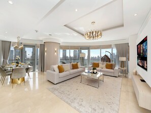 Uma sala de estar moderna com um sofá grande, uma mesa de centro e uma área de refeições com mesa de vidro.