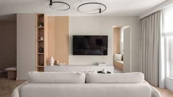 Quarto moderno com uma cama grande, televisão na parede e mesa de cabeceira com abajur.