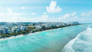 Paisagem costeira com uma praia, águas turquesa cristalinas e edifícios altos.