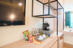 Quarto de hotel com minibar, cafeteira e diversos petiscos e bebidas.