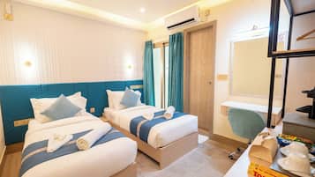 Quarto de hotel com duas camas, uma escrivaninha com cadeira, um espelho e uma janela com cortinas.