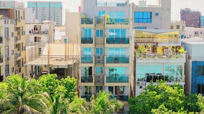 Edifício de vários andares com varandas, grandes janelas e uma obra em construção no térreo.