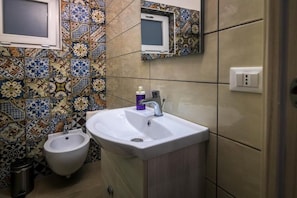 Casa de banho com bidé, pia e espelho.