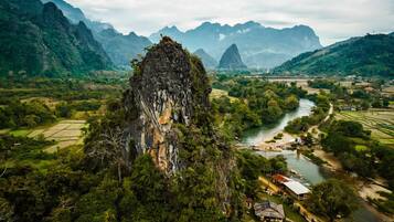 Paisagem montanhosa com uma formação rochosa imponente, um rio e edifícios dispersos.
