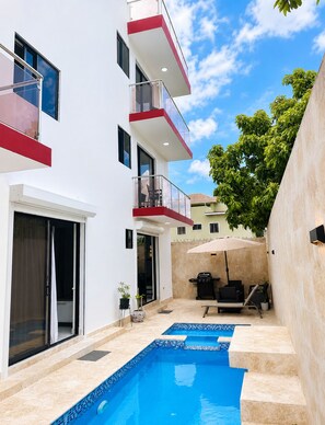Um edifício moderno com piscina, área de estar ao ar livre e churrasqueira.