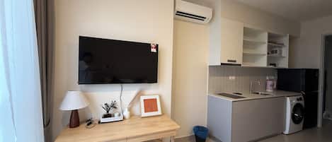 Cozinha moderna com máquina de lavar embutida, televisão de tela plana na parede e pequena mesa de jantar com luminária.