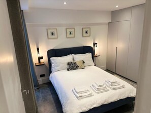 Quarto de hotel com cama, luminárias de cabeceira, guarda-roupa e obras de arte na parede.
