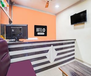 Bancada de recepção de hotel com uma placa que diz 'HOTELO Company Serviced'.