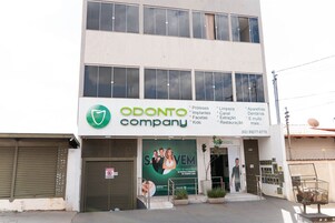 Um edifício com vários andares com uma placa da 'ODONTO company' anunciando serviços odontológicos.