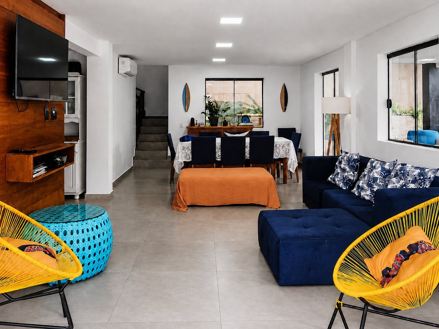 Uma sala de estar moderna com televisão, área de refeições e assentos.