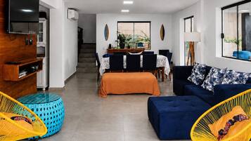 Uma sala de estar moderna com televisão, área de refeições e assentos.